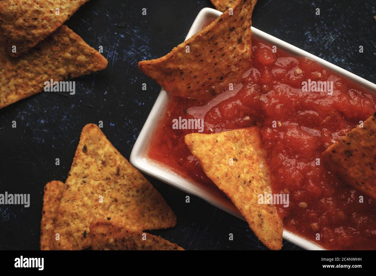High angle closeup shot of triangular potato chips dipped in tomato ...