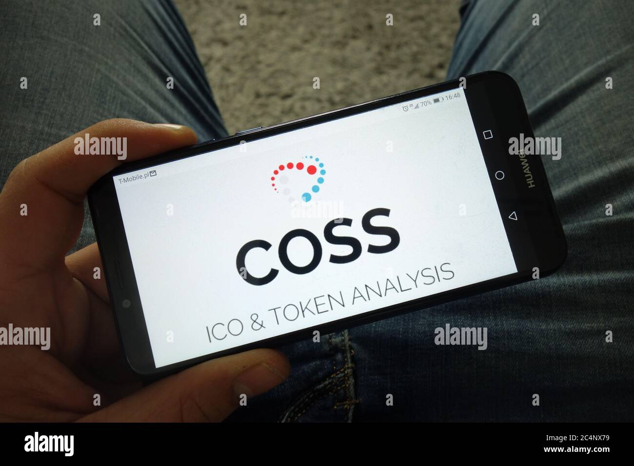 Man holding smartphone with COSS cryptocurrency exchange logo Stock ...