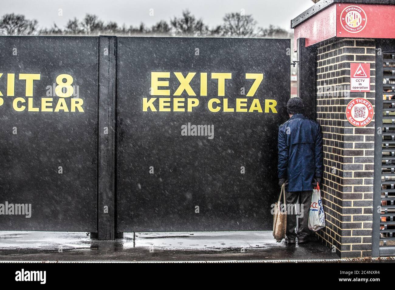 Football fan watches match through gap in exit gate. Taking advantage ...