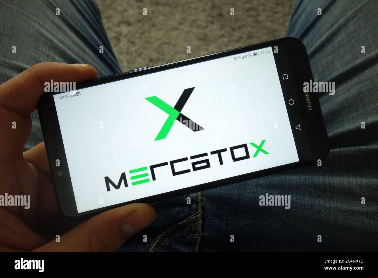 Man holding smartphone with Mercatox cryptocurrency exchange logo Stock Photo - Alamy