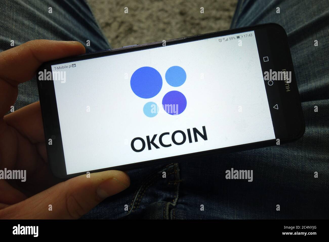 Man holding smartphone with Okcoin cryptocurrency exchange logo Stock ...