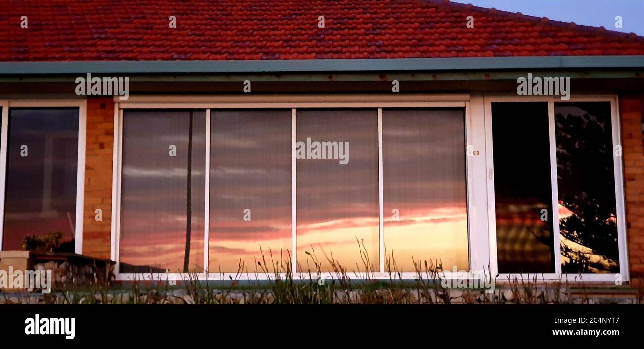 Panoramic shot of a beautiful sunset reflected in the windows of a ...