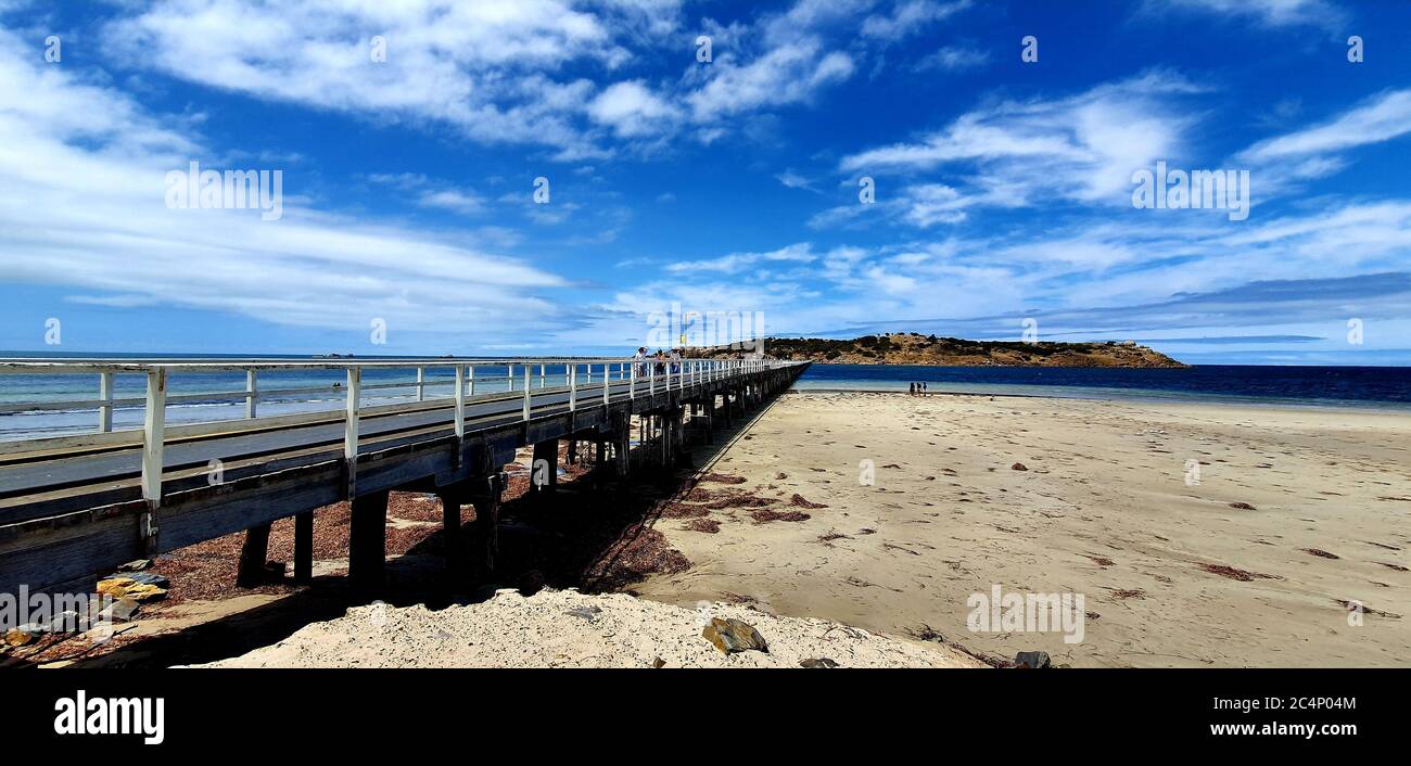 Panoramic shot of a deck leading to the sea under a blue cloudy sky ...