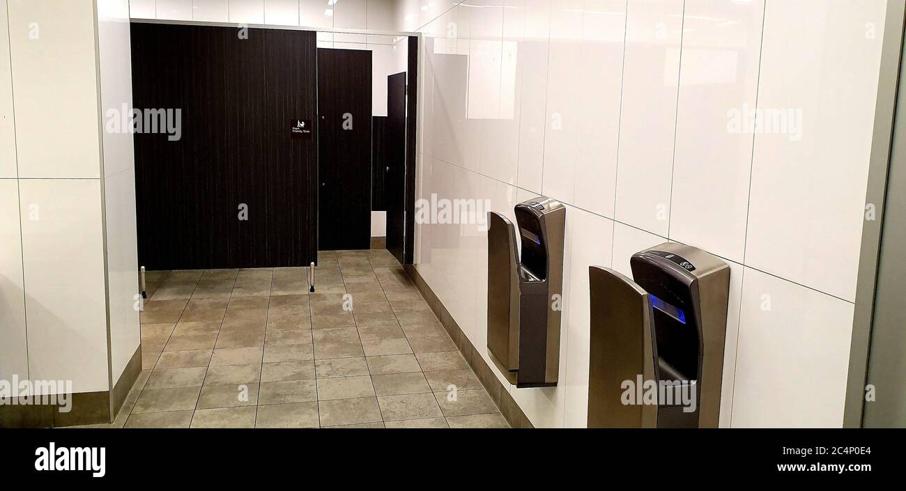 Panoramic shot of an empty restroom with white walls and gray tiles ...