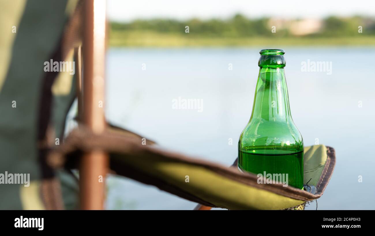 Green beer bottle. Outdoor recreation. Camp chair Stock Photo - Alamy