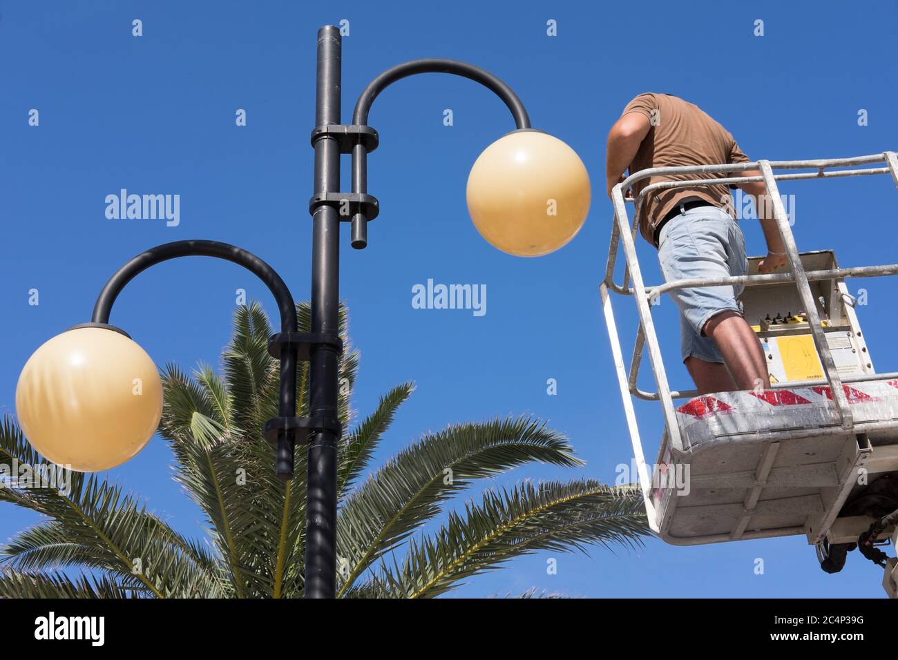 Italian man stands on aerial platform and replaces the lights of street ...