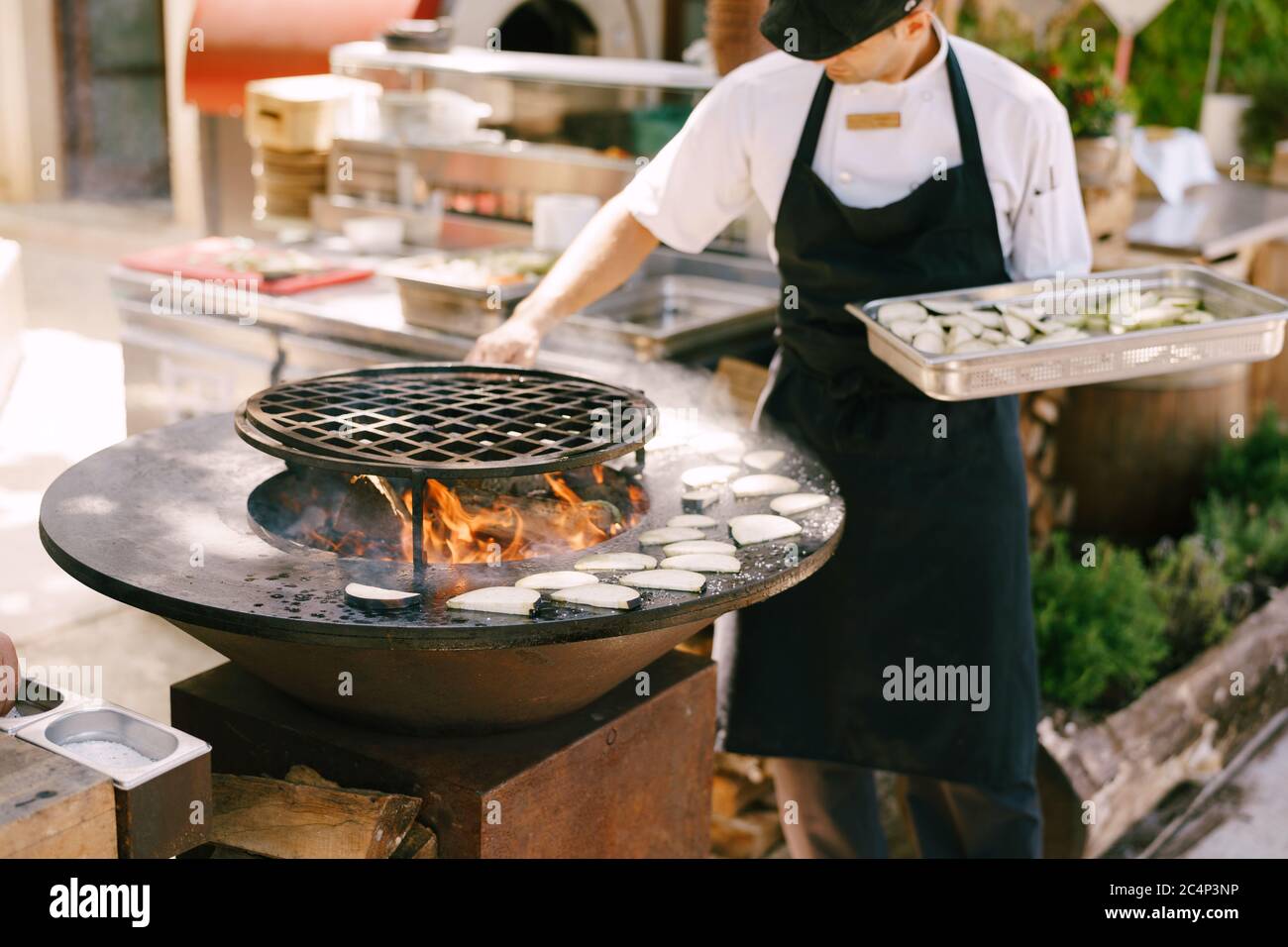 The cook roasts the courgettes. Grilled vegetables. Round bowl-shaped ...