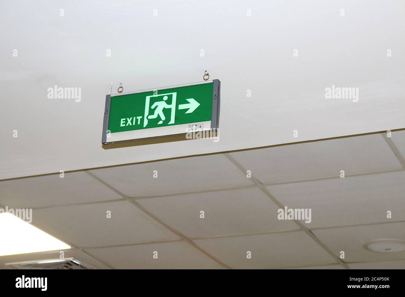 Green and white exit sign hanging from ceiling Stock Photo - Alamy