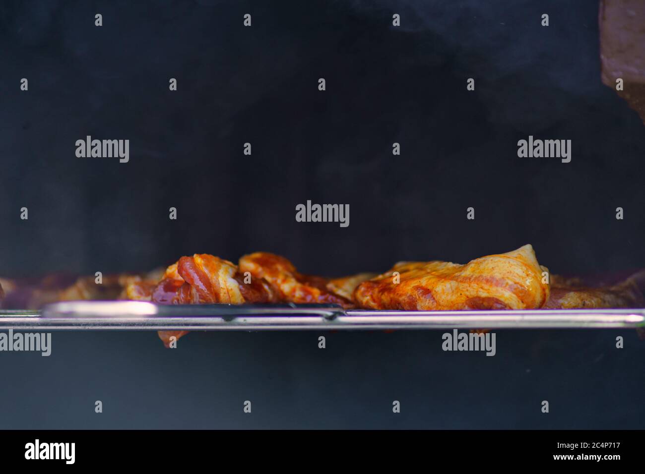 Grilled meat at the roast, tasty hot meal in preparation in the dust of ...