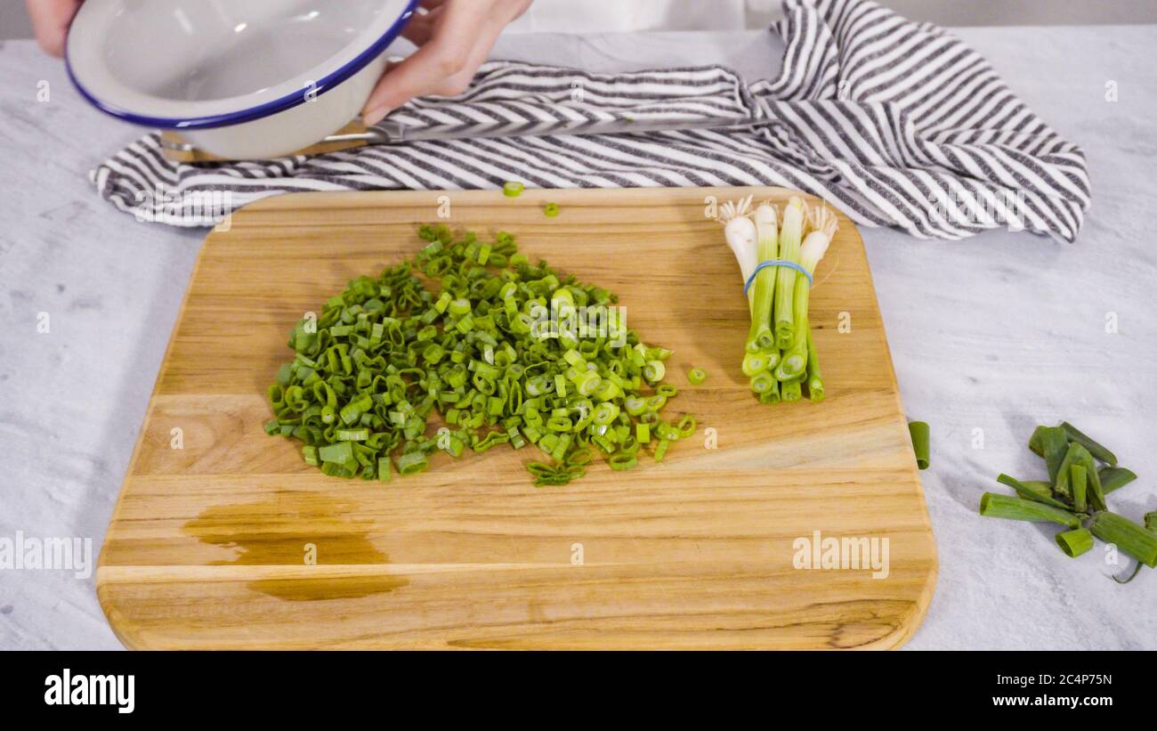 Step by step. Chopping organic green onions on a wood cutting board ...
