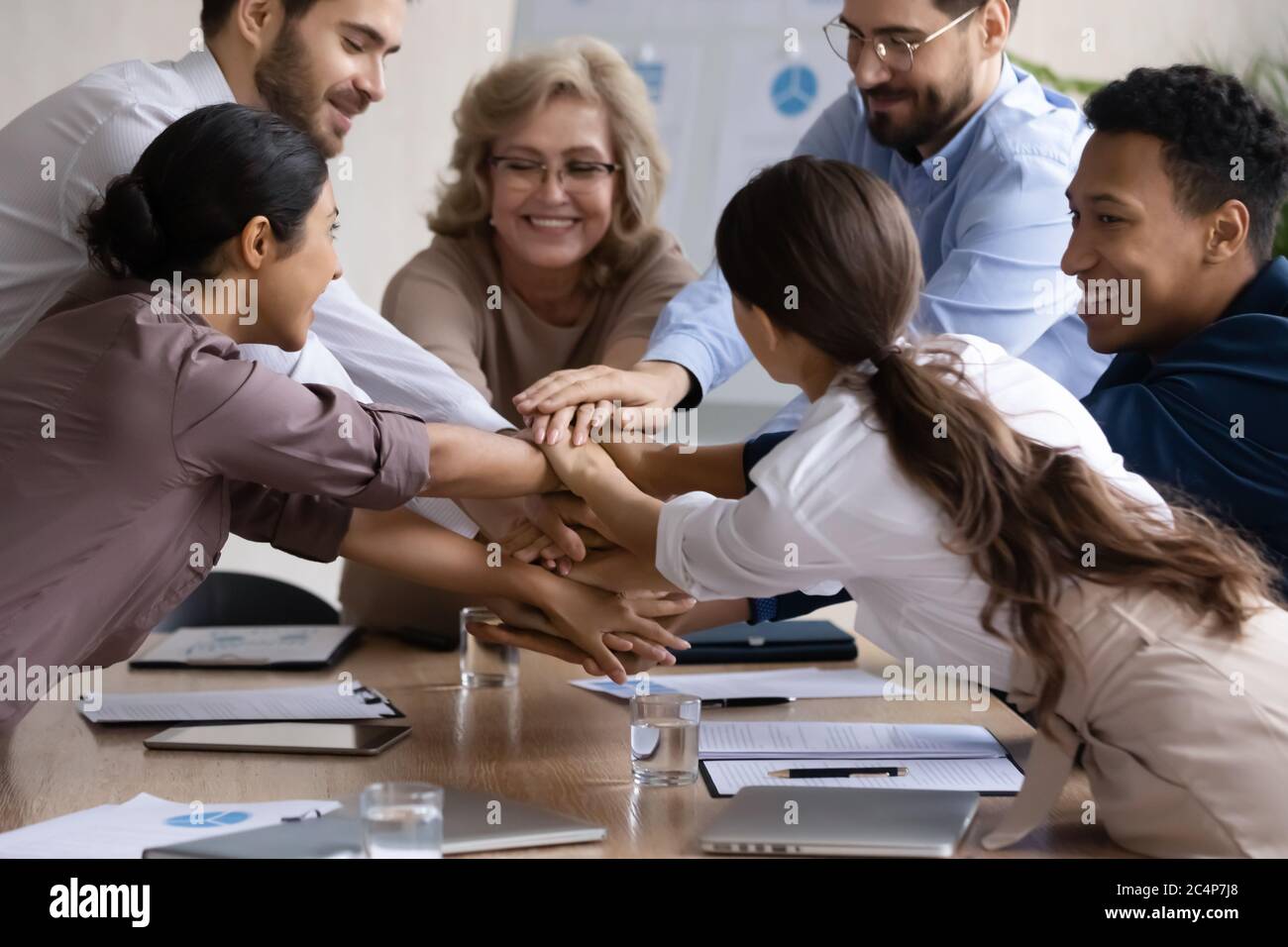 Overjoyed diverse employees stacking hands together, sharing success ...