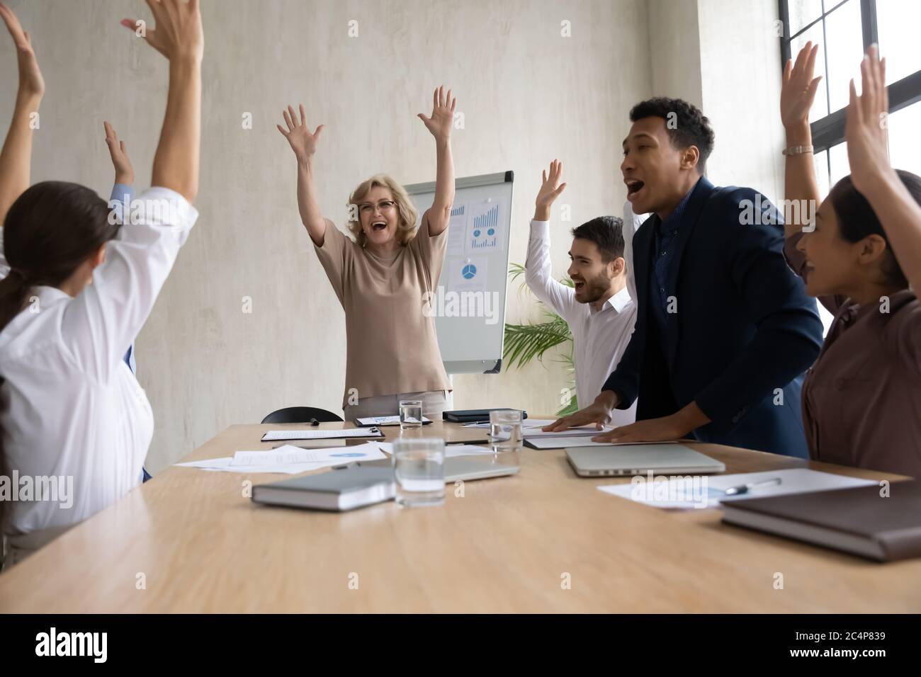 Excited diverse employees team celebrating success, raising hands and ...
