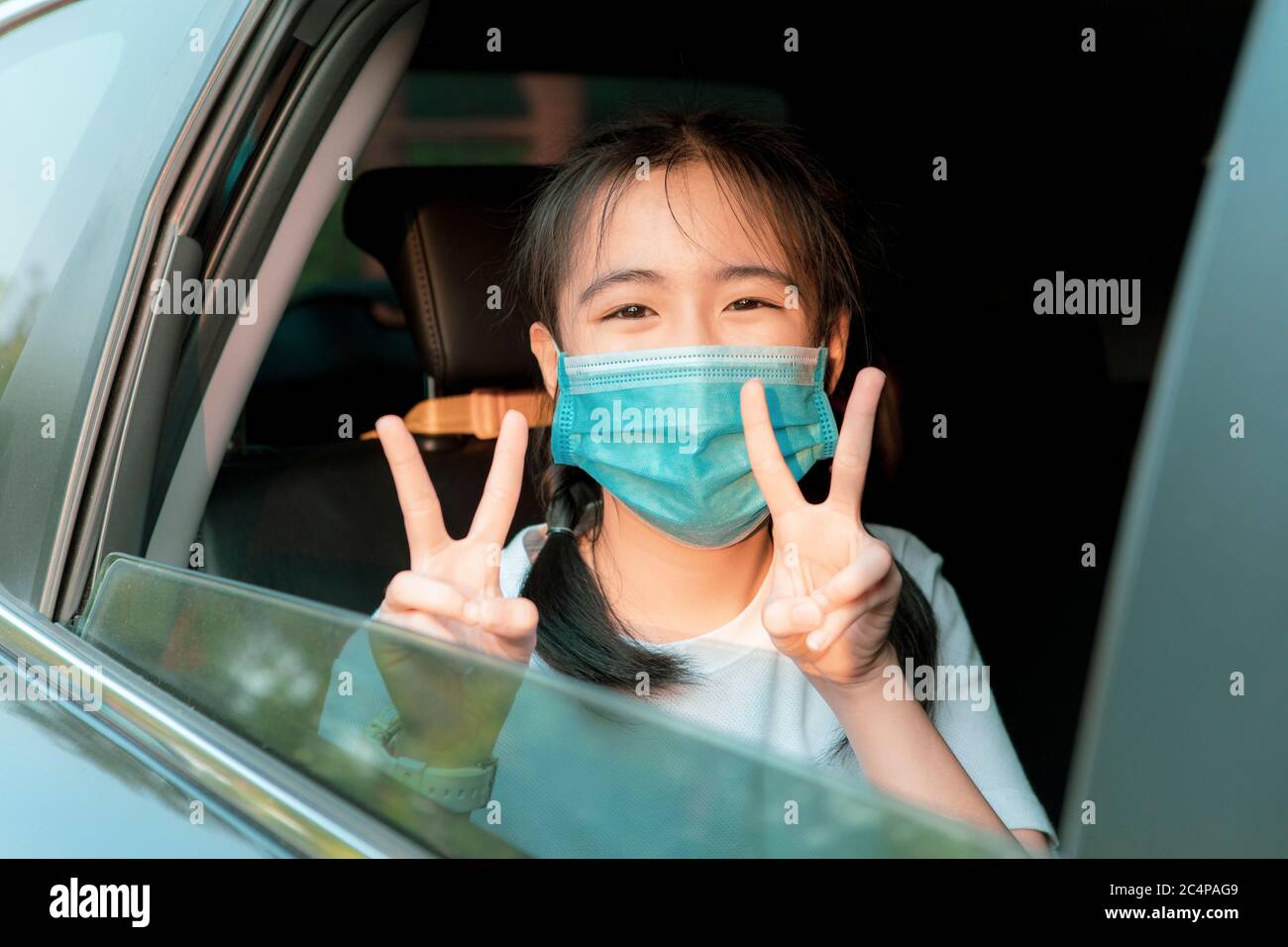 asian teenager wearing protection mask rising victory sign in passenger ...