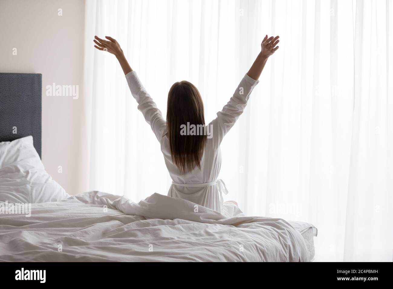 Back view of young female stretch in bed Stock Photo - Alamy