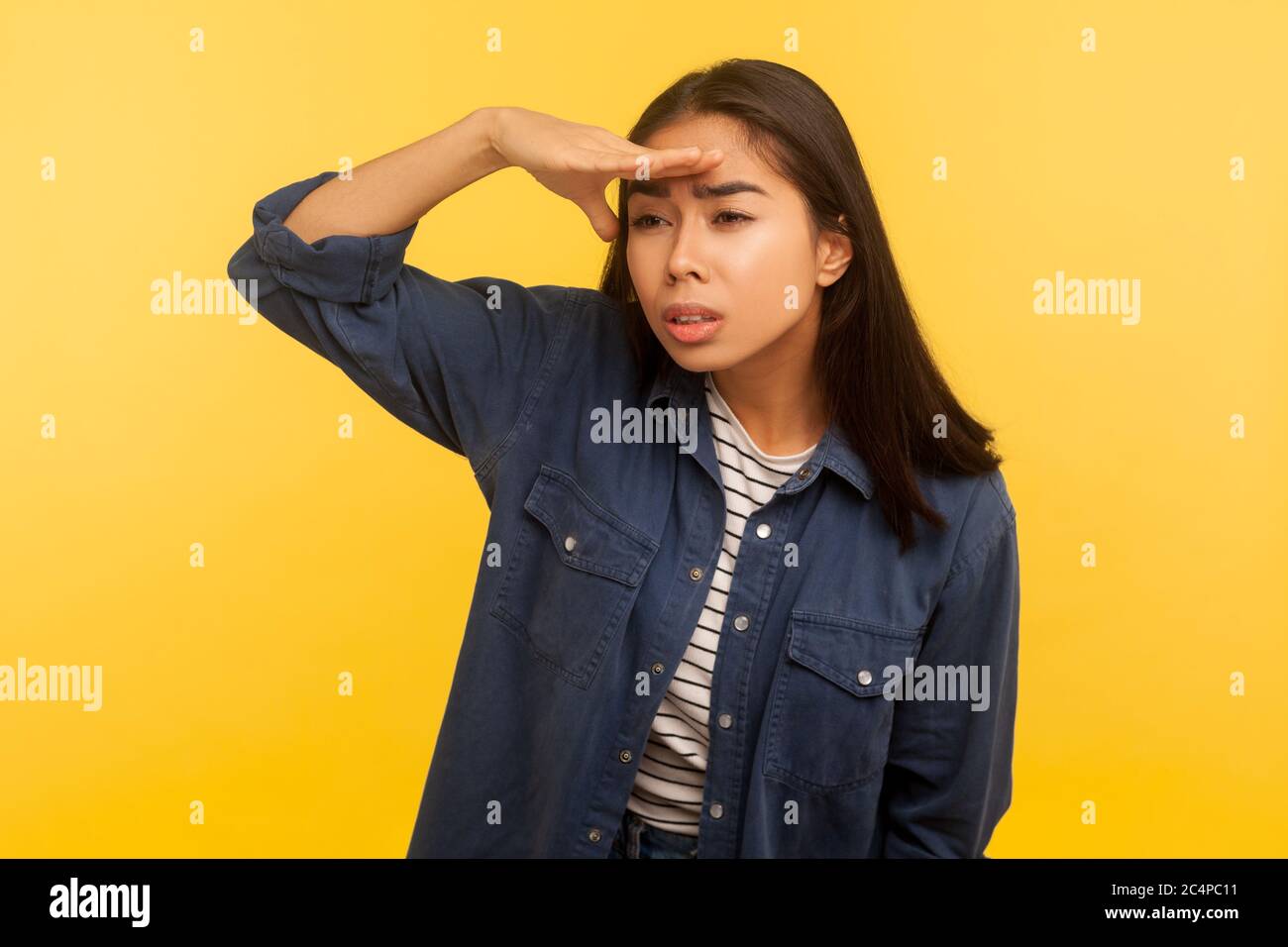 Portrait of curious girl in denim shirt looking carefully far away with ...