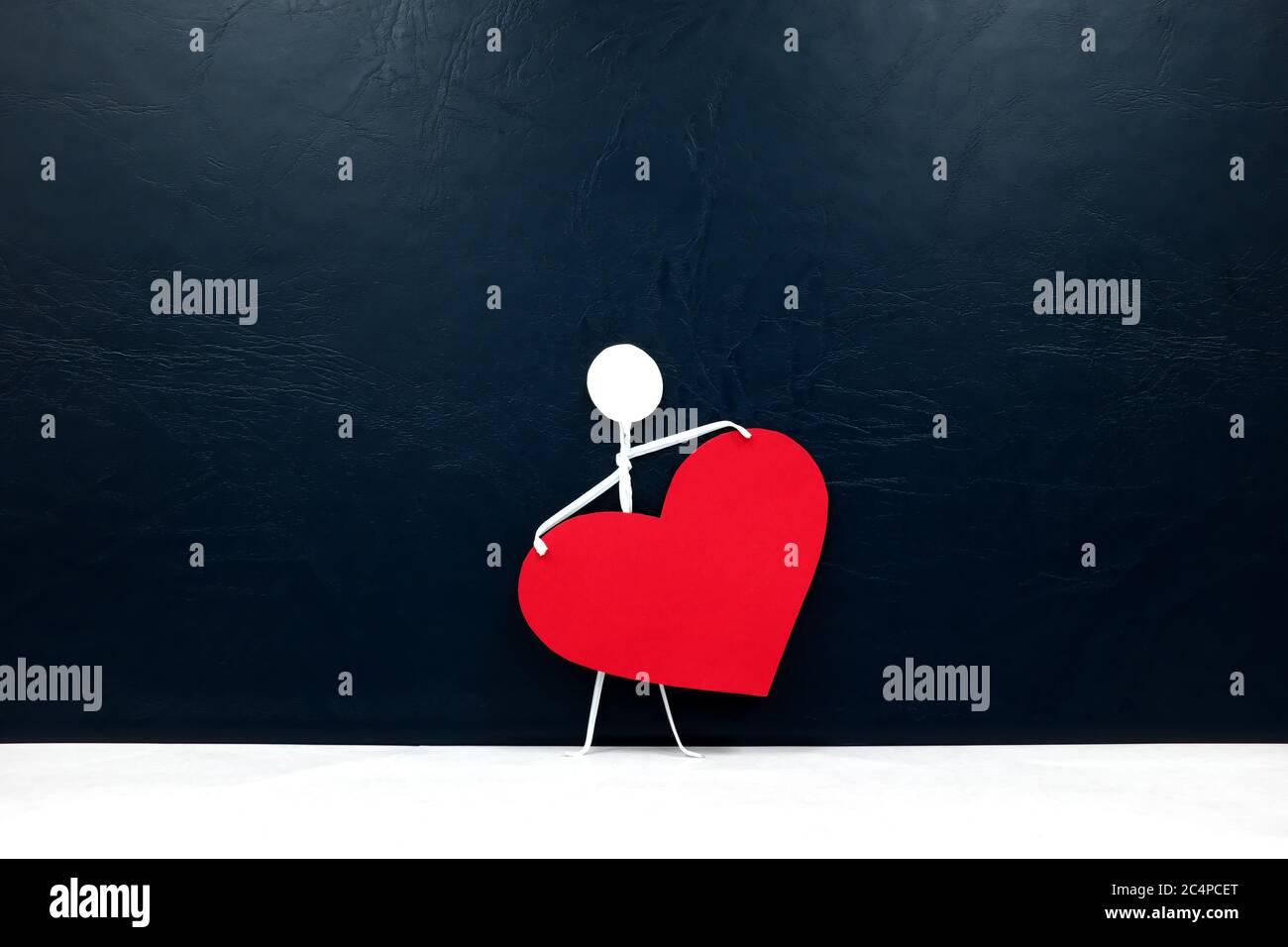 Human stick figure holding a big red heart in dark background. Give ...