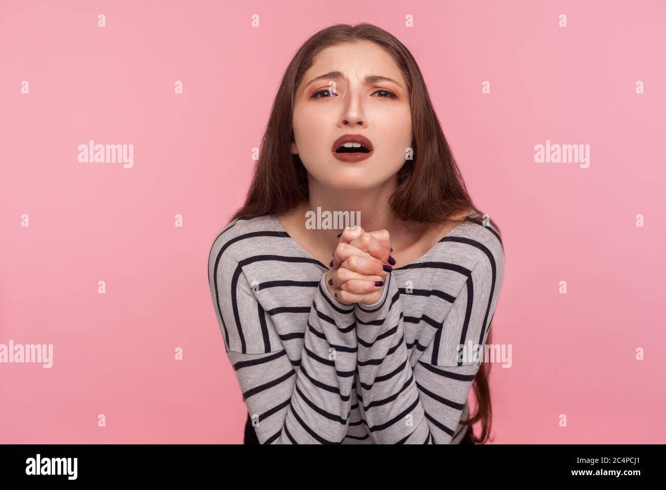 Please, I'm begging! Portrait of woman in striped sweatshirt praying ...