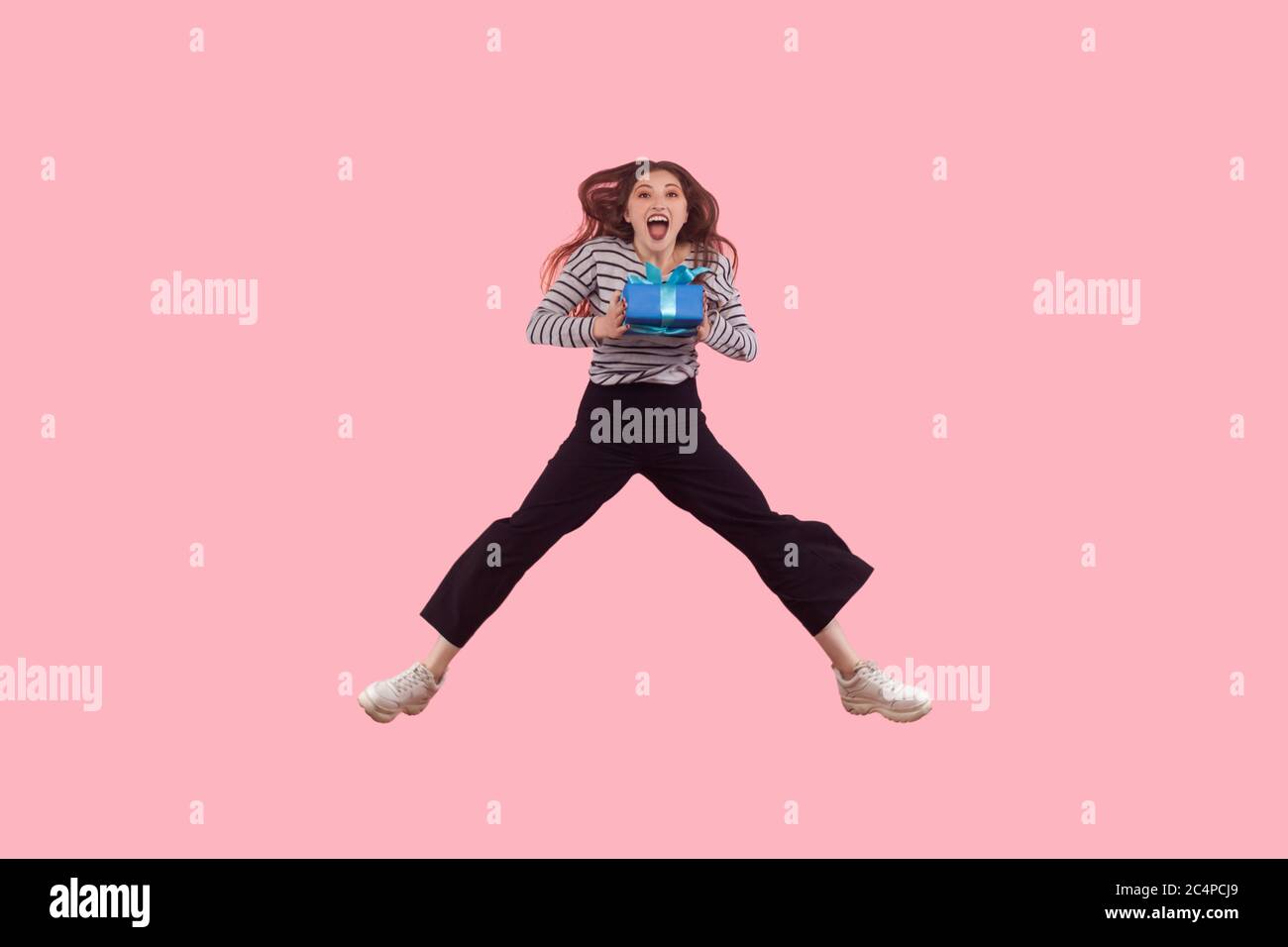 Full length side view, energetic woman jumping and flying with gift box ...