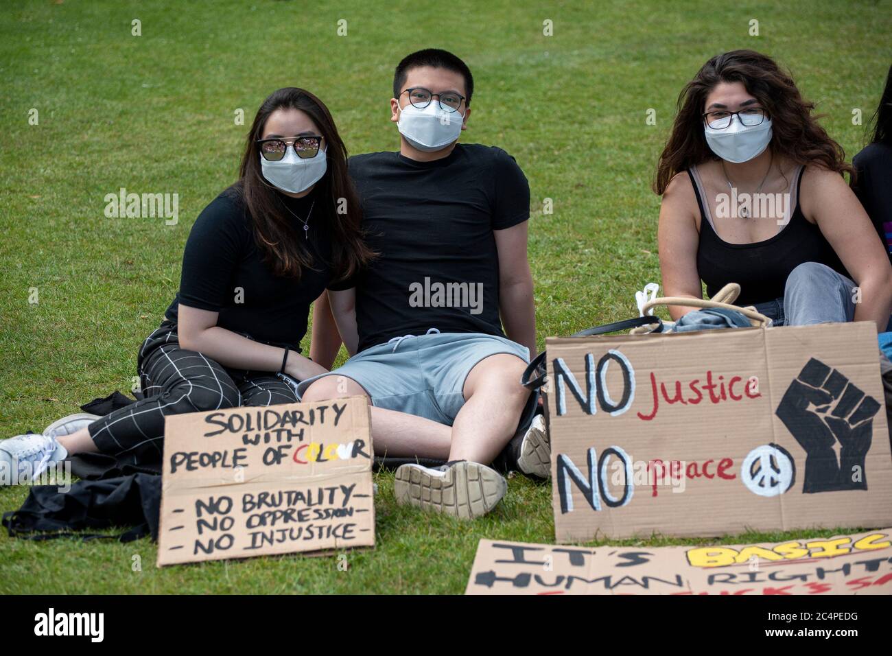 Three young people sat in the park at the gathering of the BLM ...