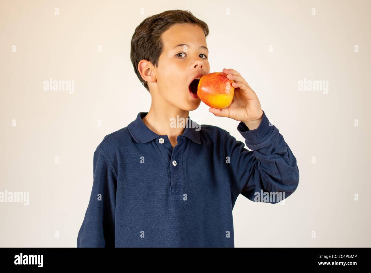 Smiling young boy eating an apple Stock Photo - Alamy
