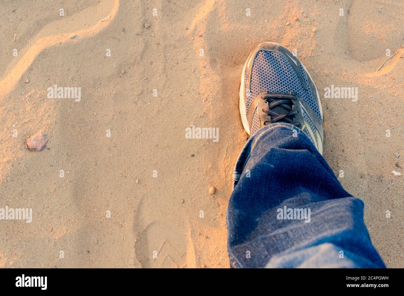 Top down view of man extending a foot with a worn sneaker jeans on ...