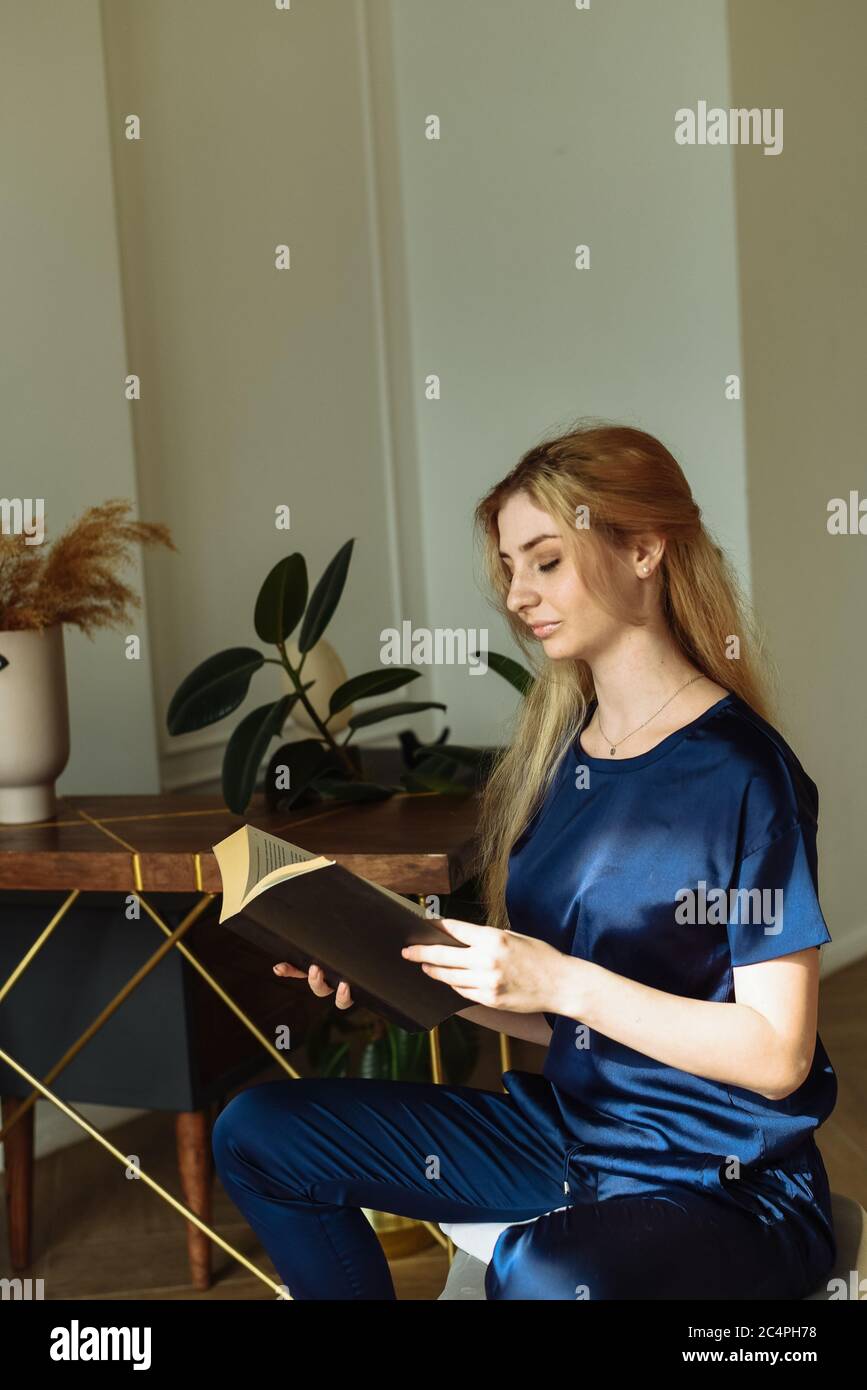 Young beautiful student in home pajamas is sitting at home and is ...