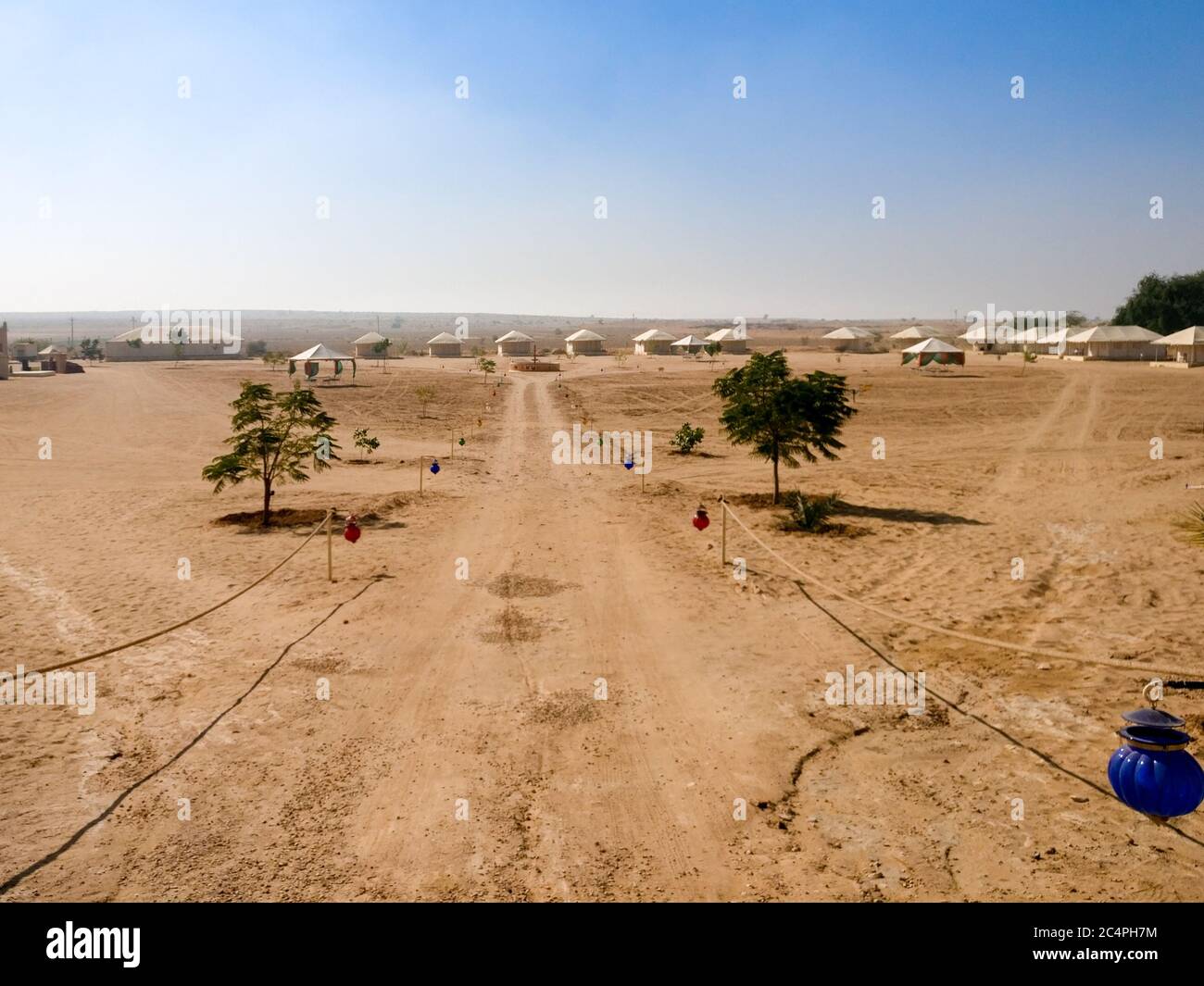 Empty dirt road with barren desert on both sides and blue sky above ...