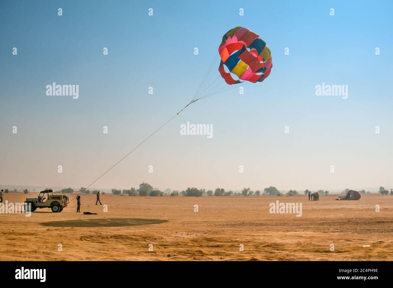 Jeep towing a parachute for adventure para gliding in the empty barren ...