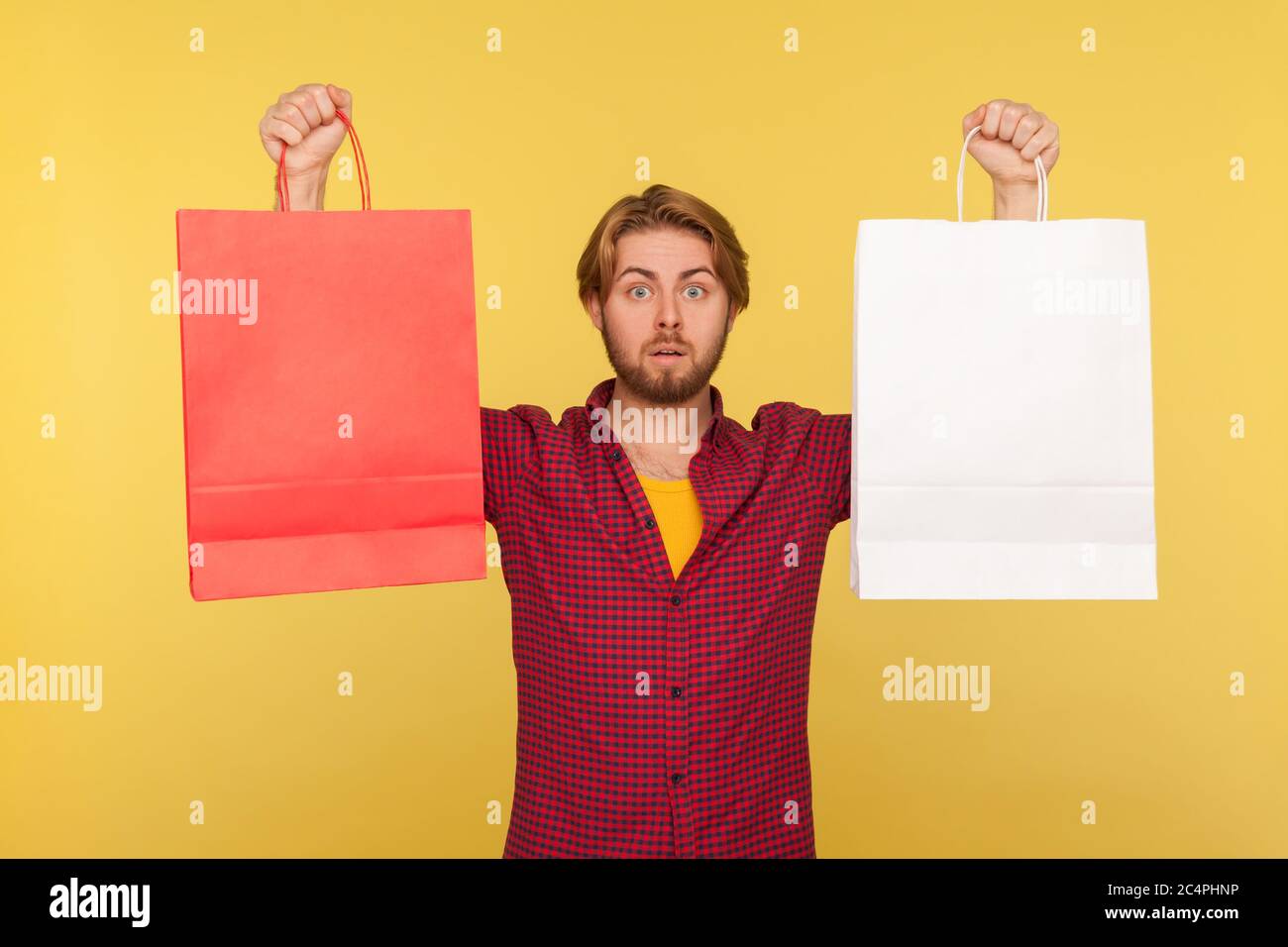 Surprised shopper guy in checkered shirt raising shopping bags blank ...