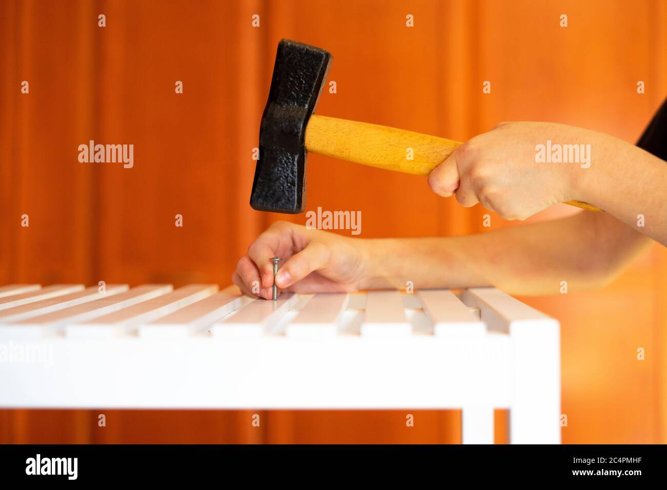 Man putting a screw into a piece of furniture with a hammer. Concept of ...