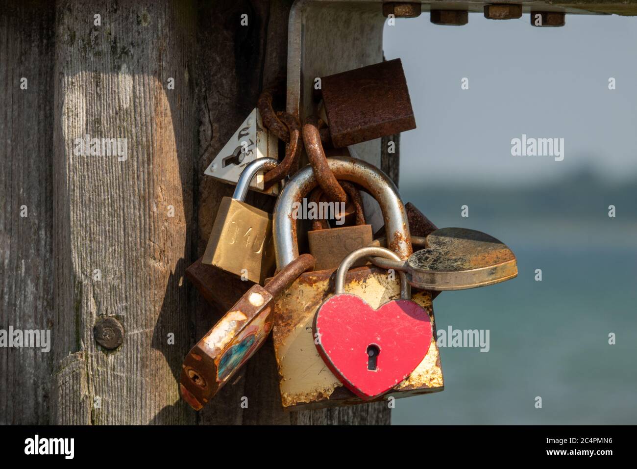 different coloured padlocks hang as a bundle on a wooden railing Stock ...