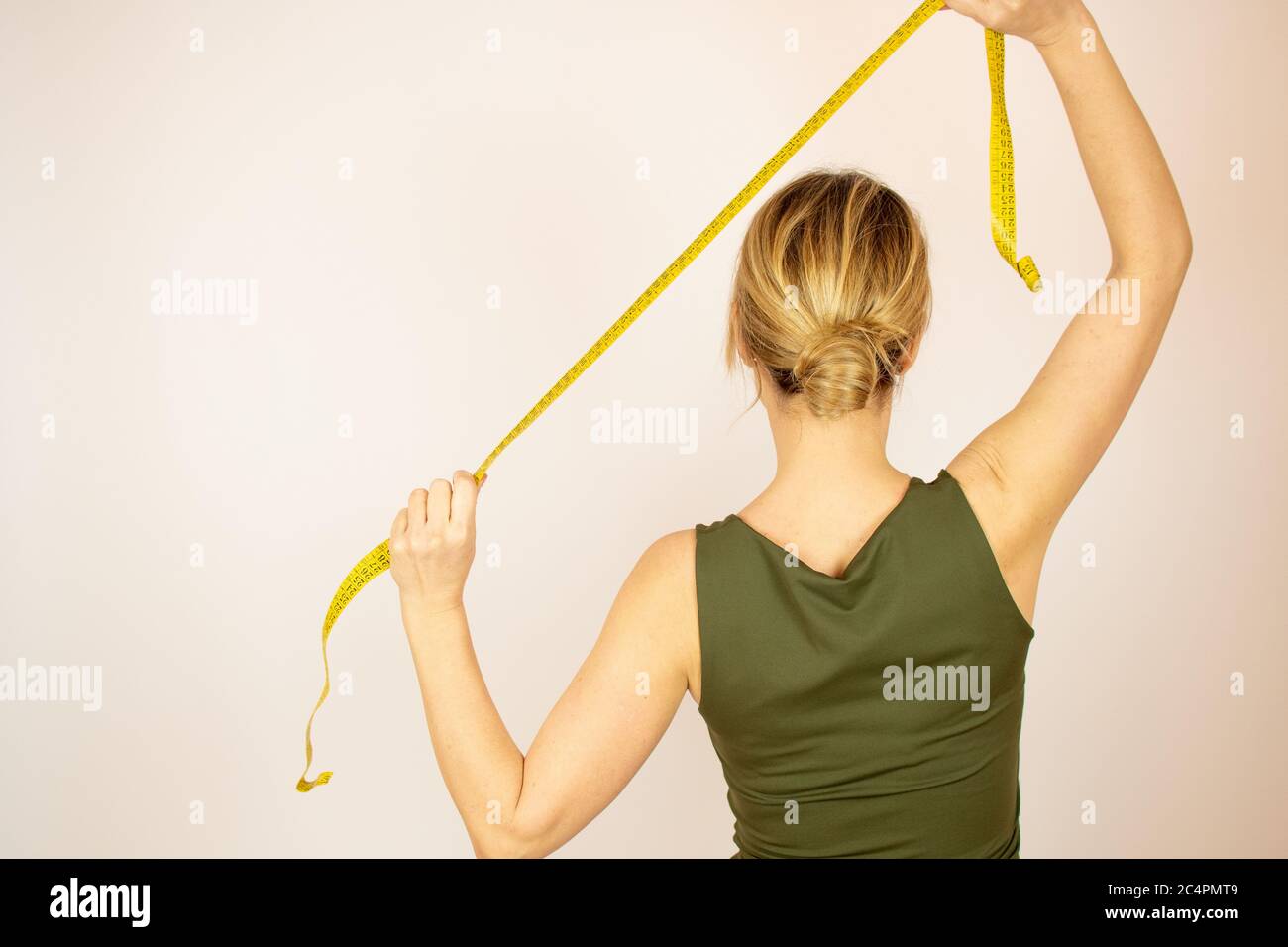 Blond woman on back with tape measure in hands Stock Photo - Alamy