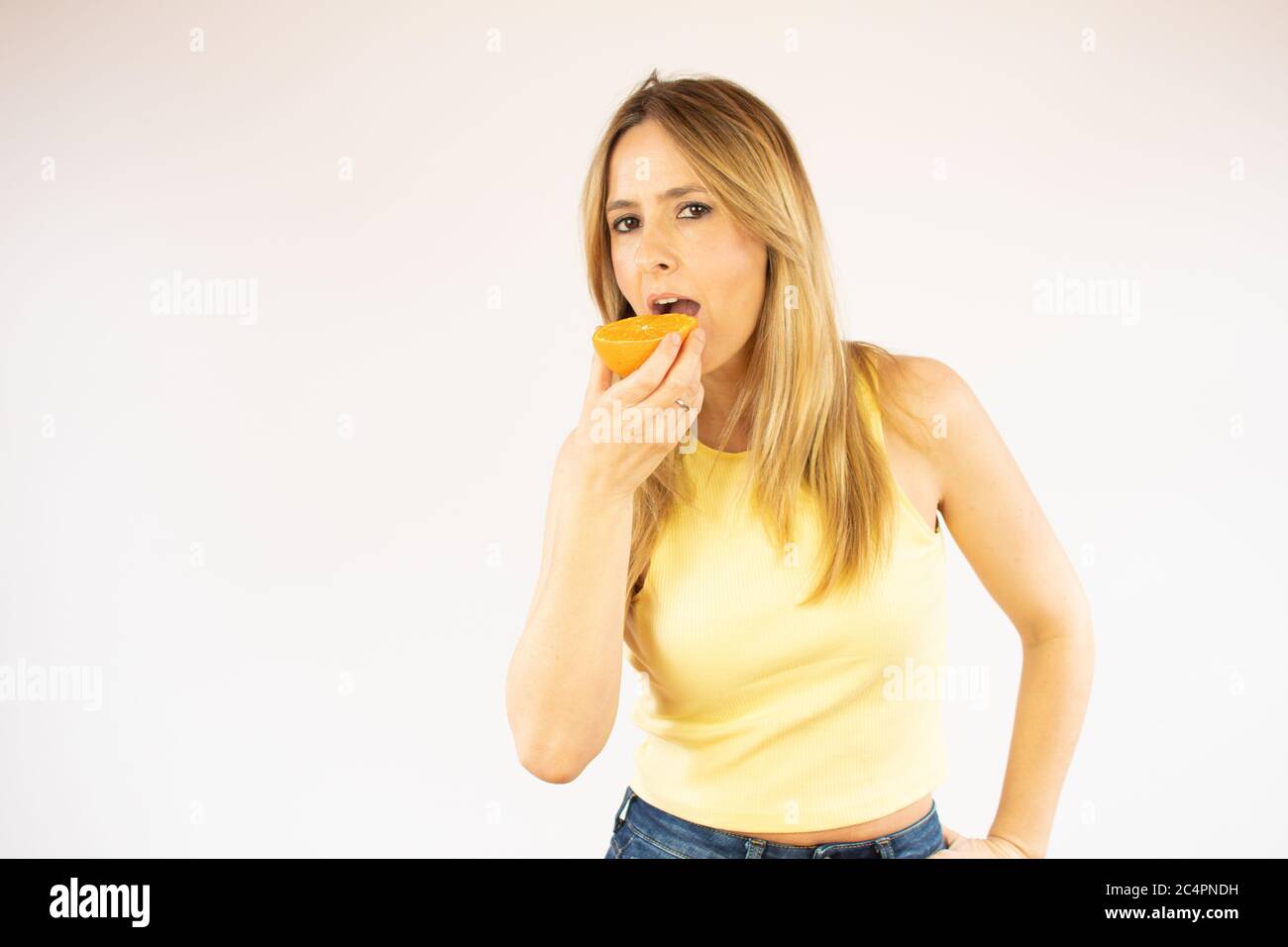 Beautiful woman eating an orange Stock Photo - Alamy