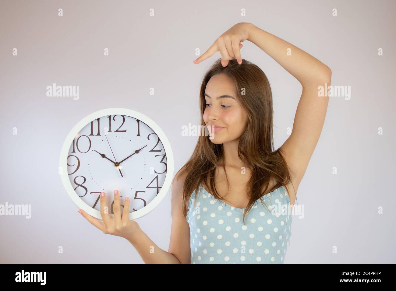 Pretty young girl in dress looking at a big clock Stock Photo - Alamy