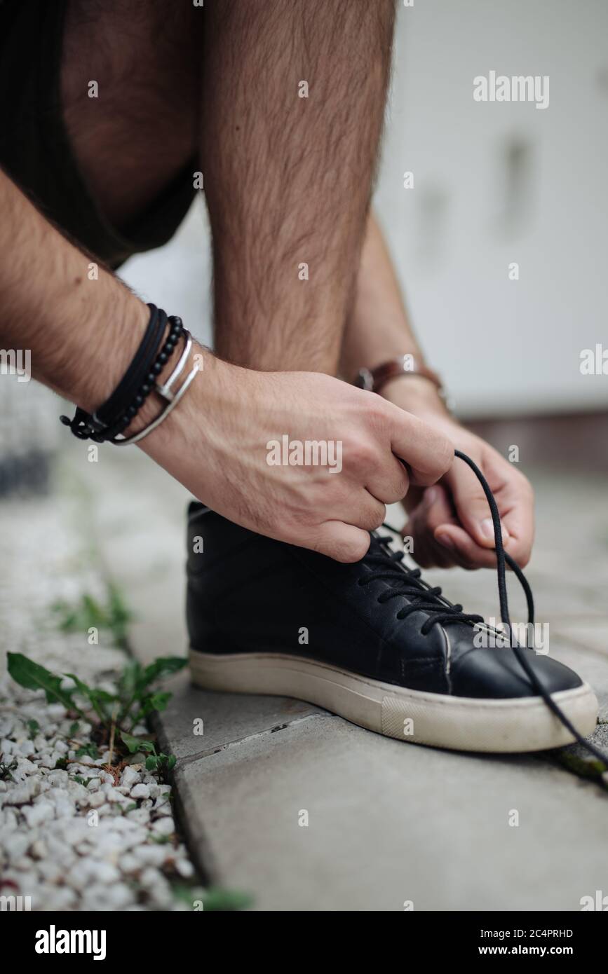 Urban young guy tying his shoe on getting ready to go Stock Photo - Alamy