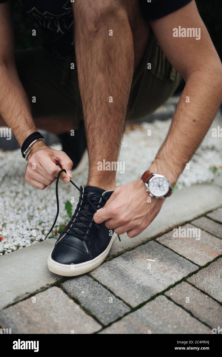 Urban young guy tying his shoe on getting ready to go Stock Photo - Alamy