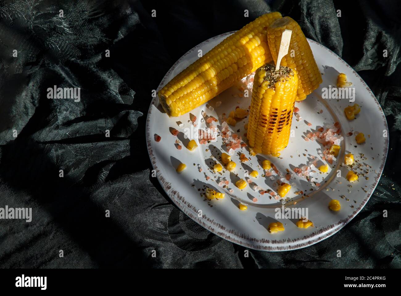 Grilled corn on the cob on classic white plate over dark background ...