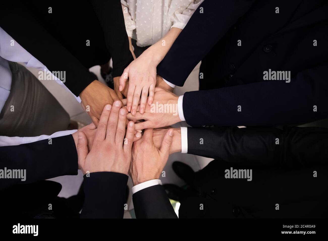 Multiracial business people stacking hands together top view close up ...