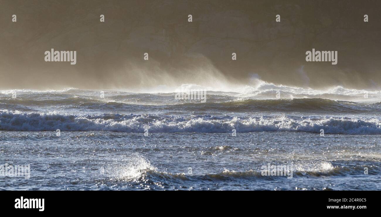 a windy day at the coast with a spray or mist blowing from the top of ...