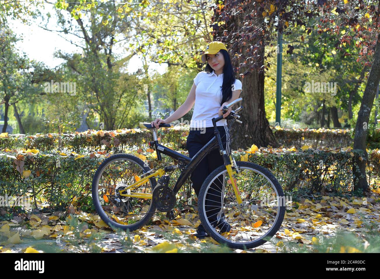Portrait of a young lady riding the bicycle in the park on an Autumn ...