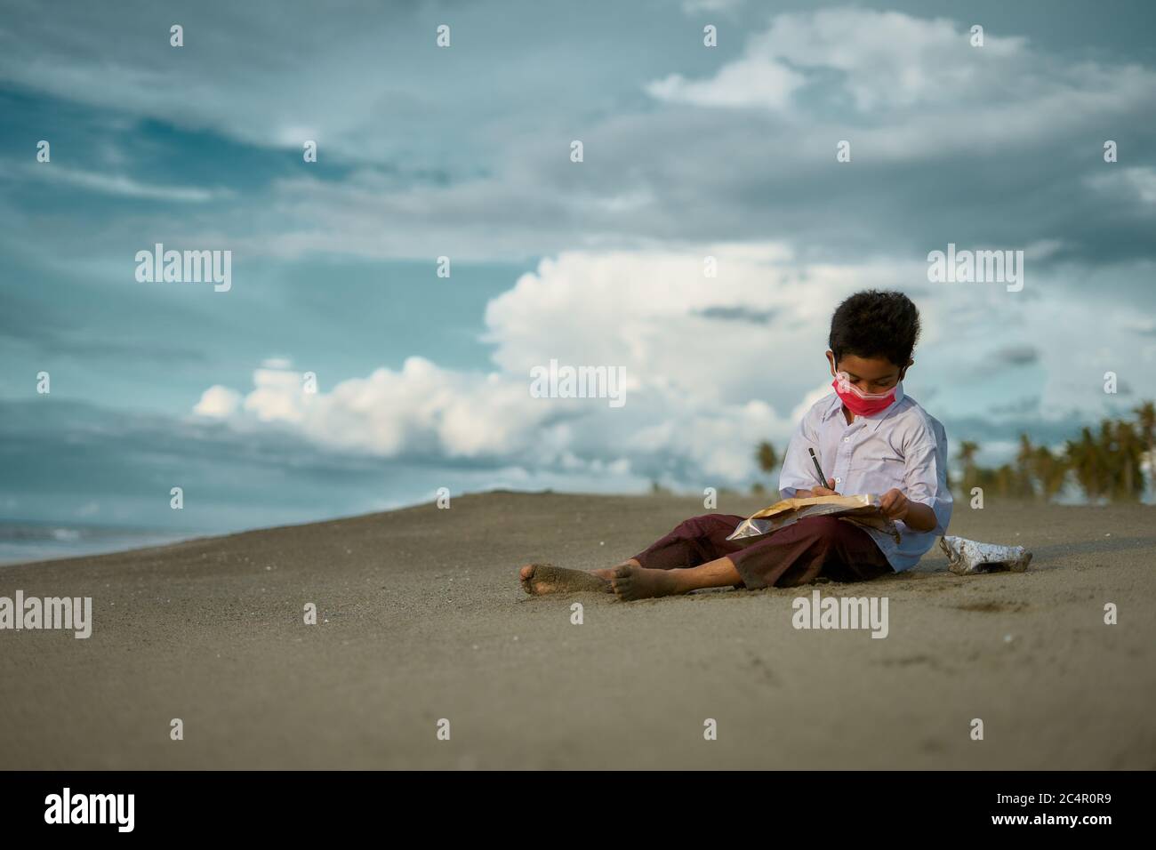 Little boy study hard, doing homework outdoor under cloud and blue sky ...