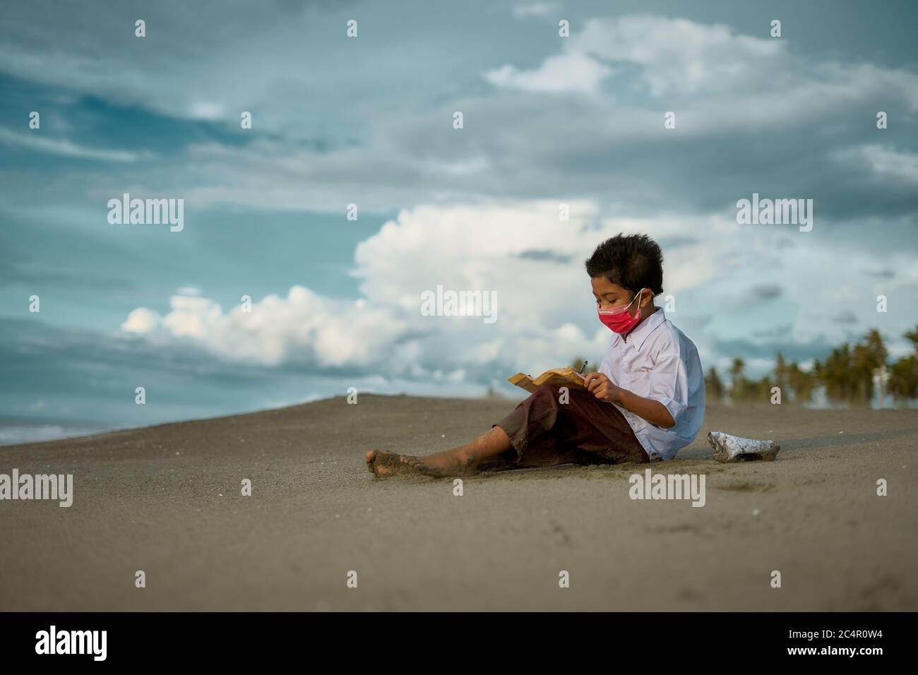 Little boy study hard, doing homework outdoor under cloud and blue sky ...