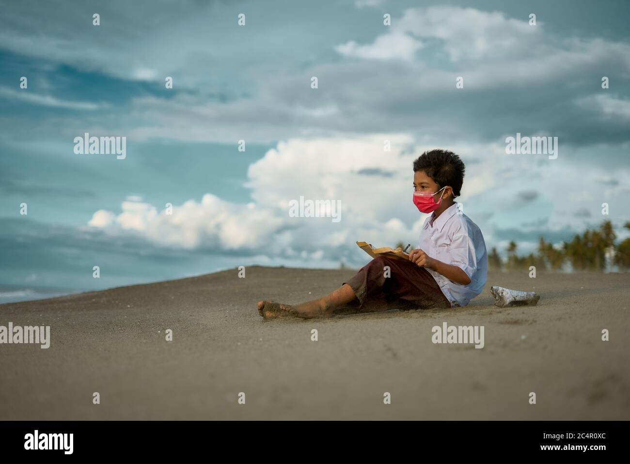 Little boy study hard, doing homework outdoor under cloud and blue sky ...