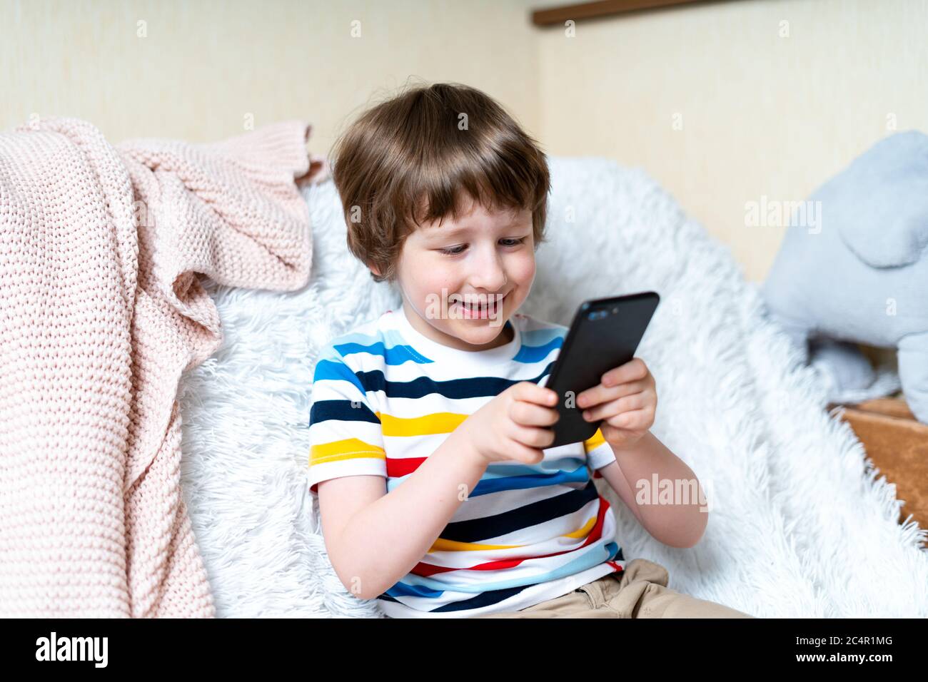 Happy little child boy playing online game, watching video on cellphone ...