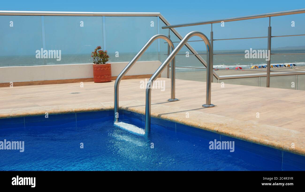 Corner of a swimming pool with marble border, blue ceramic walls and ...