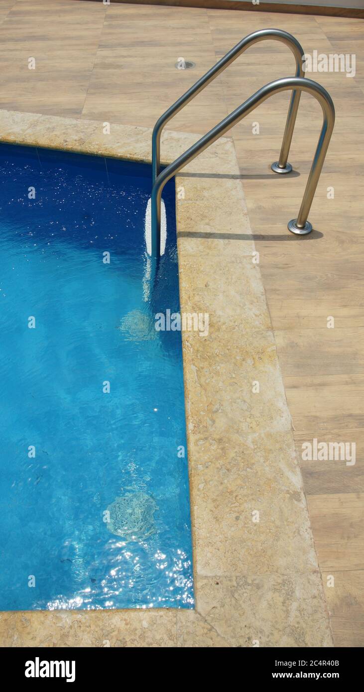 Close-up of corner of a swimming pool with marble border and blue ...