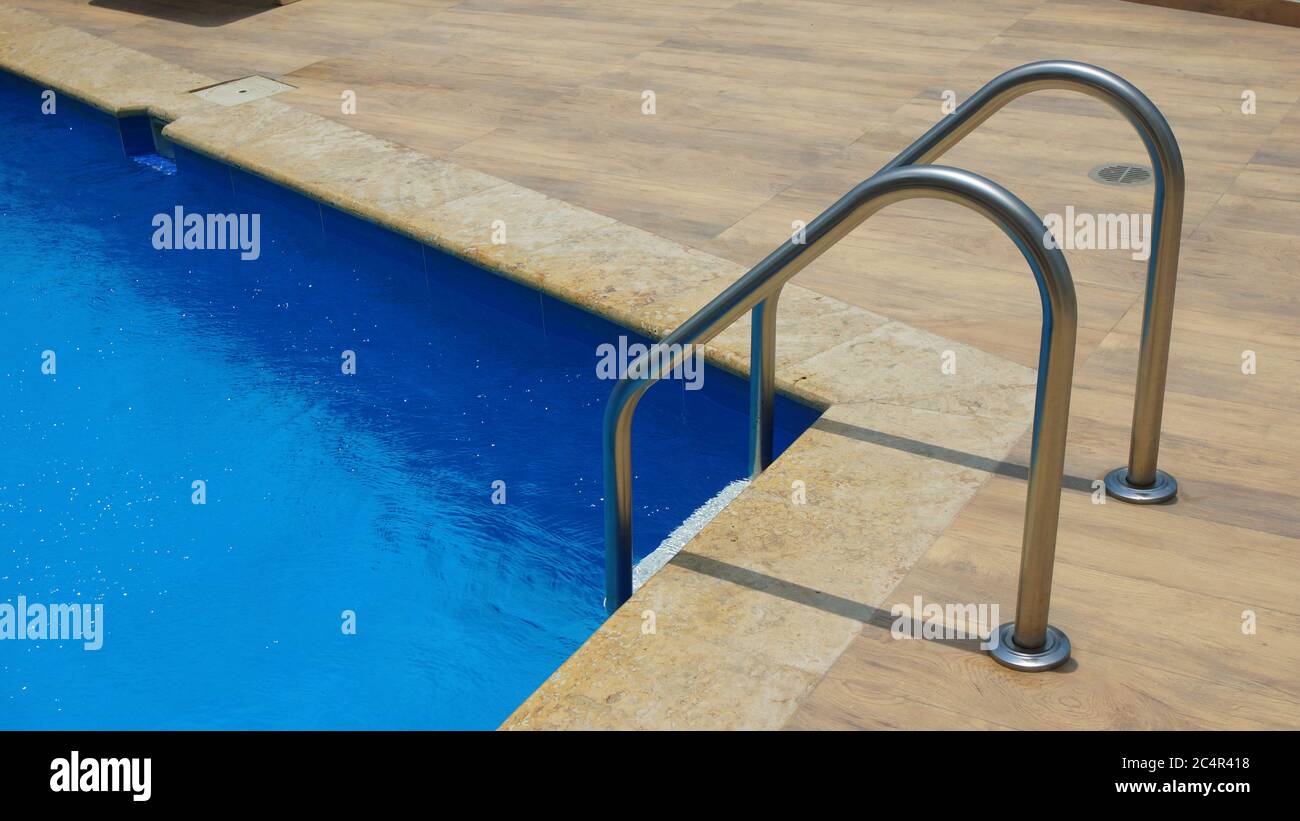 Corner of a swimming pool with marble border, blue ceramic walls and ...