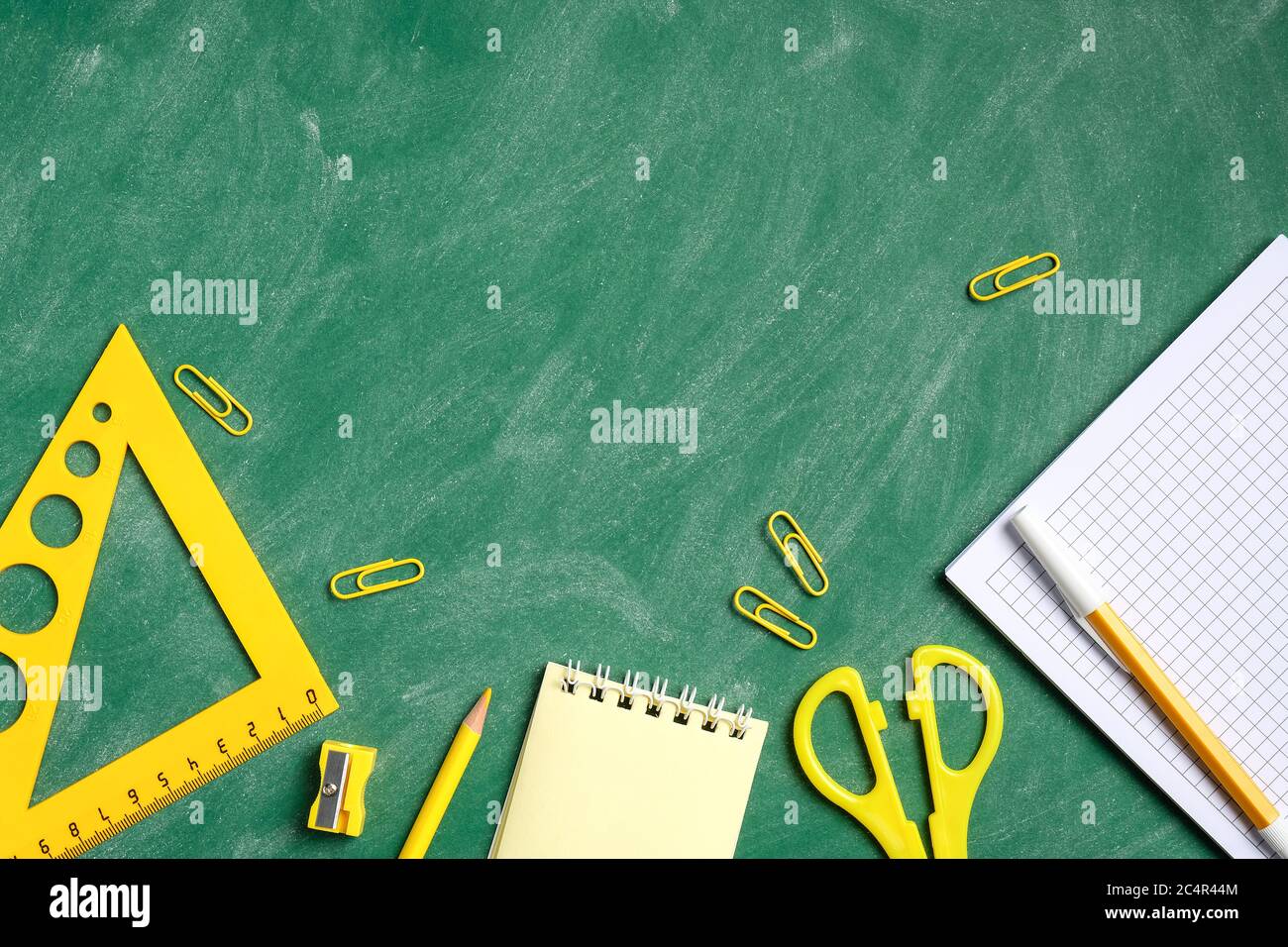 Yellow school supplies on green chalkboard background. Back to school ...