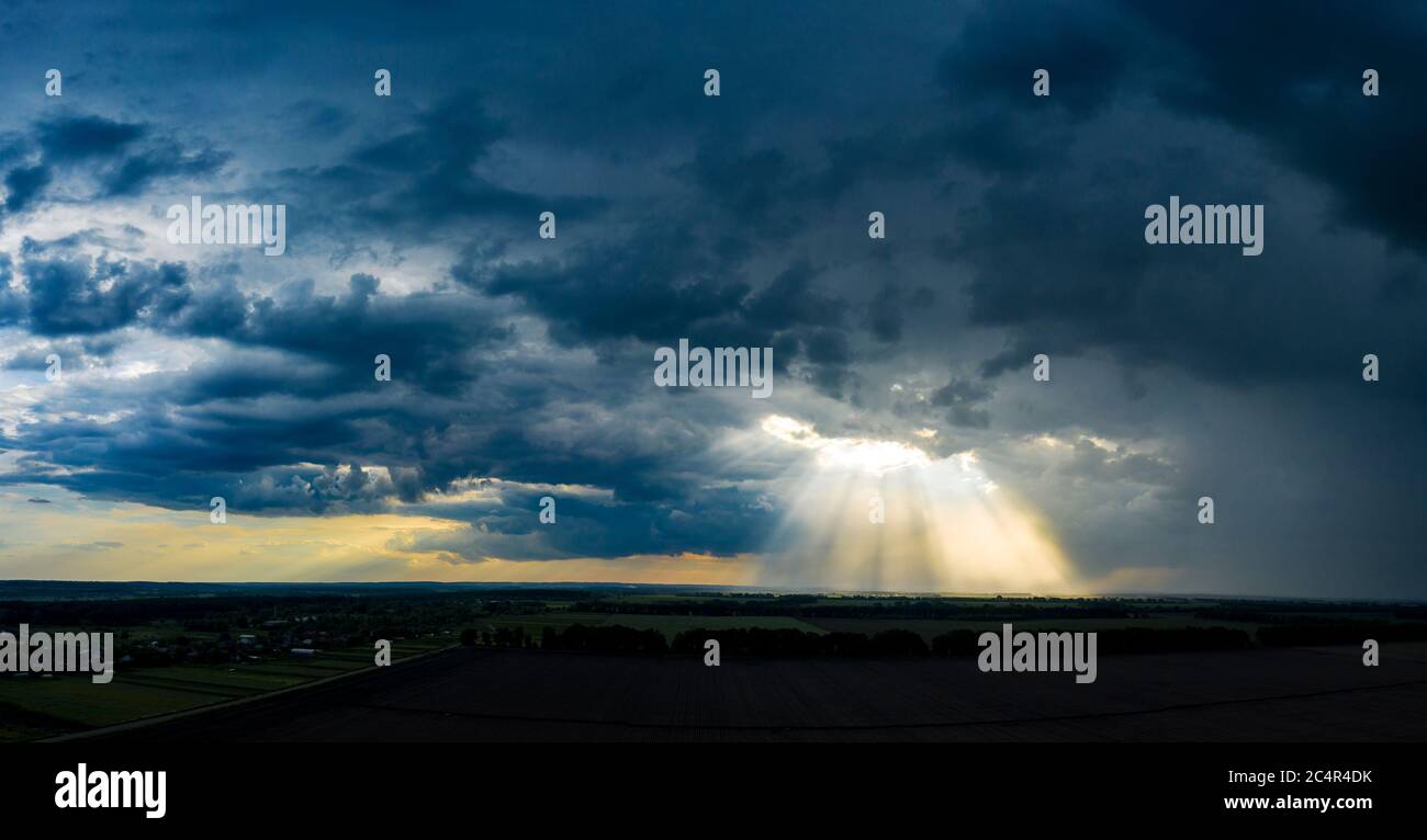 Aerial flying above stunning field under dramatic rain cloud rolling ...