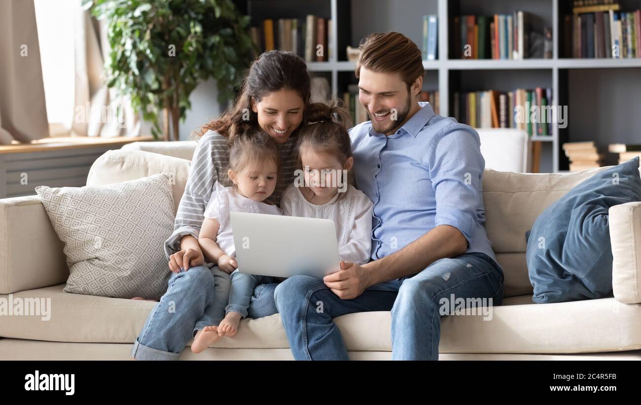 Happy parents with two little daughters using laptop together Stock ...